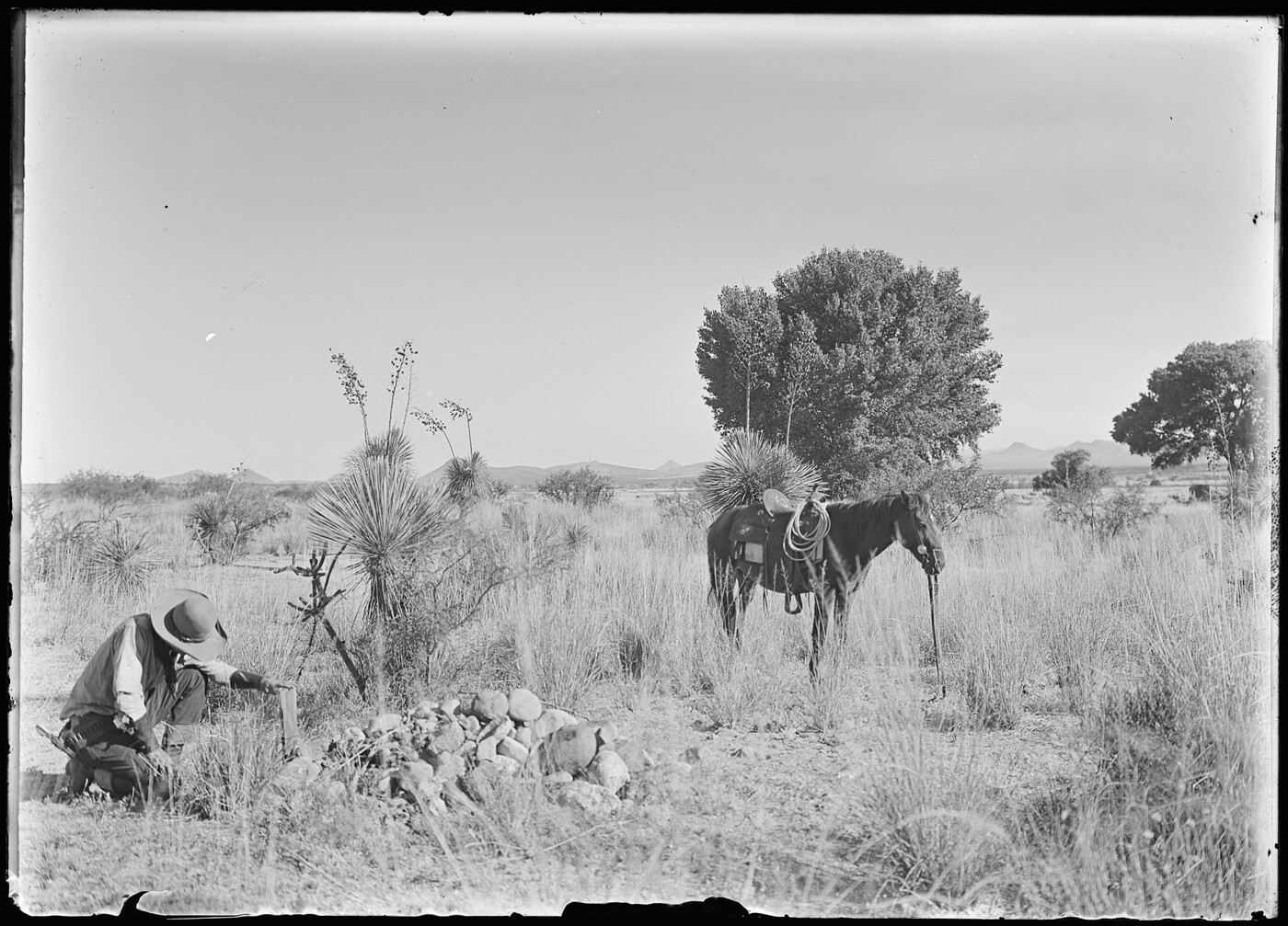 Photographer, Erwin E. Smith reading the headboard on the rock-covered ...